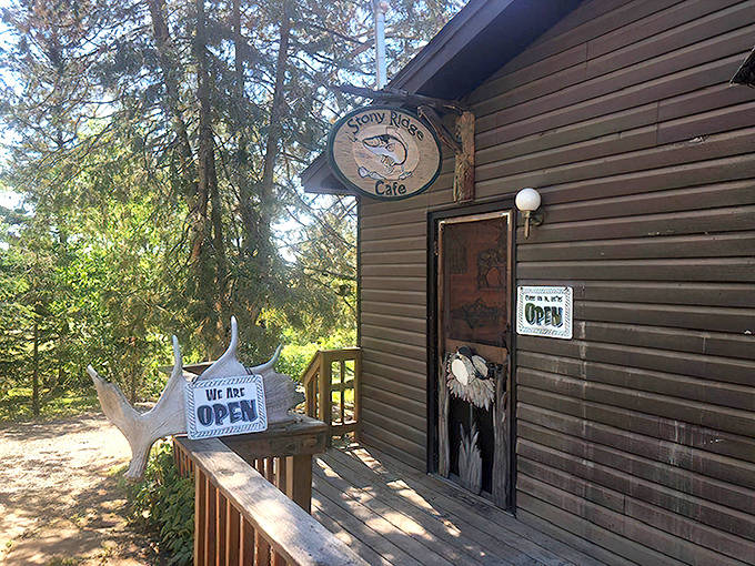 A rustic wooden cabin emerges from the pines, with an antler-adorned "OPEN" sign welcoming hungry adventurers to burger paradise.