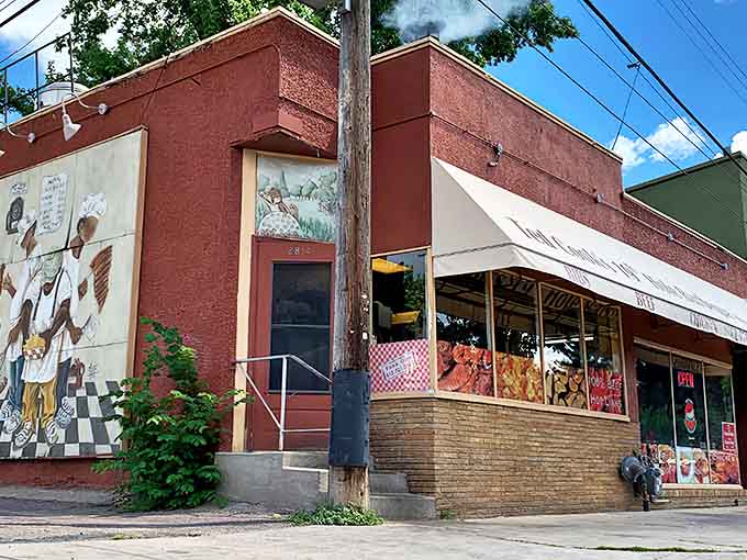 Ted Cook's brick exterior stands like a barbecue fortress, its mural promising culinary treasures within. The modest storefront belies the smoky magic happening inside.