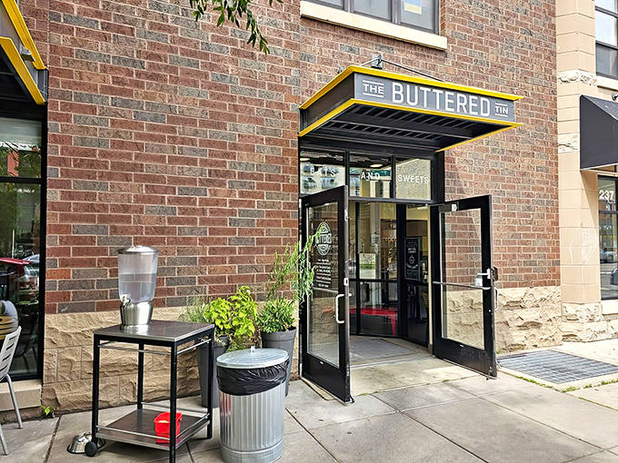 The brick facade of The Buttered Tin welcomes hungry visitors with its cheerful yellow awning &ndash; a beacon of buttery goodness in Lowertown.