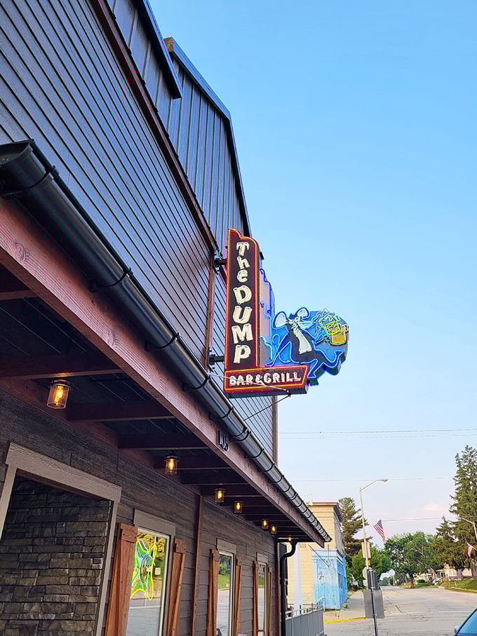 The iconic neon sign of The Dump Bar & Grill beckons hungry travelers with its playful cartoon character &ndash; a promise of cold beer and unforgettable burgers ahead.