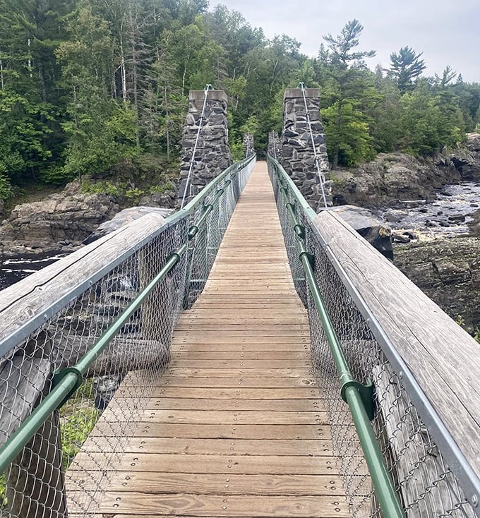 A wooden suspension bridge stretches across the gorge, inviting adventurers to cross into nature's playground.
