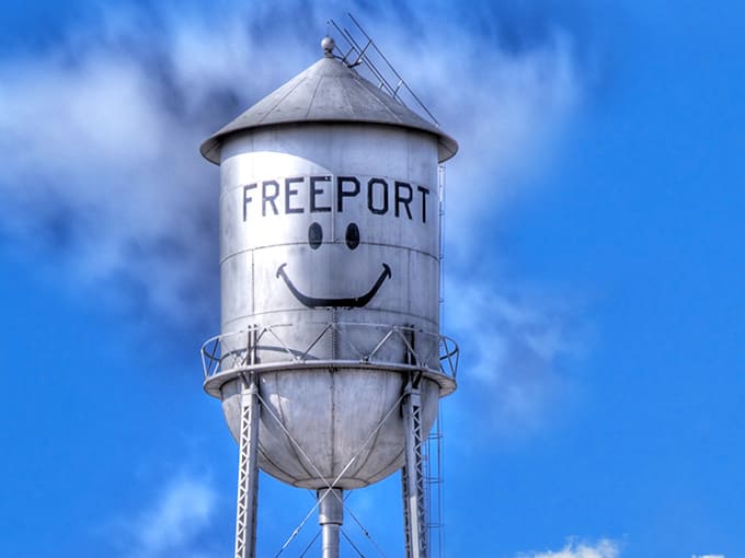 The iconic Freeport water tower stands against a brilliant blue Minnesota sky, its cheerful smile welcoming visitors from miles around.