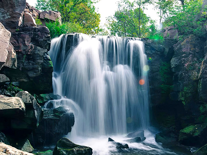 Winnewissa Falls cascades gracefully over ancient red quartzite, creating nature's perfect symphony of sound and sight.