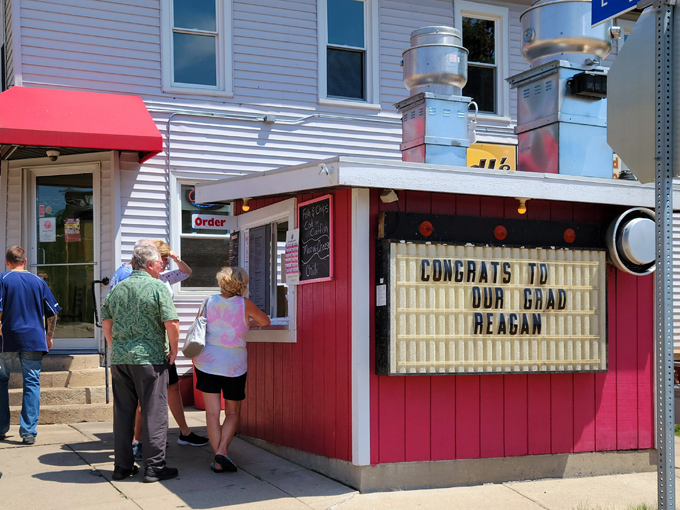 The iconic red order window at Wedl's beckons hungry travelers with its no-nonsense charm and promise of burger perfection.