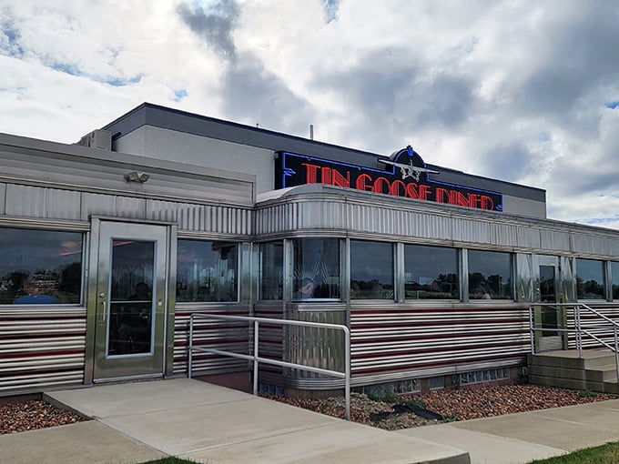 The gleaming silver exterior of Tin Goose Diner stands like a time capsule of Americana, its red neon sign beckoning hungry travelers.