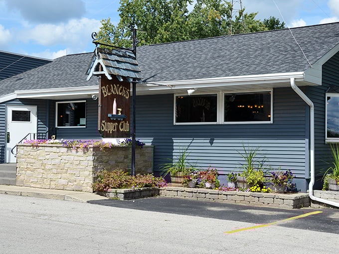 The unassuming exterior of Blanck's Supper Club, where colorful flower beds welcome visitors to this Wisconsin institution that's been serving comfort and community for generations.