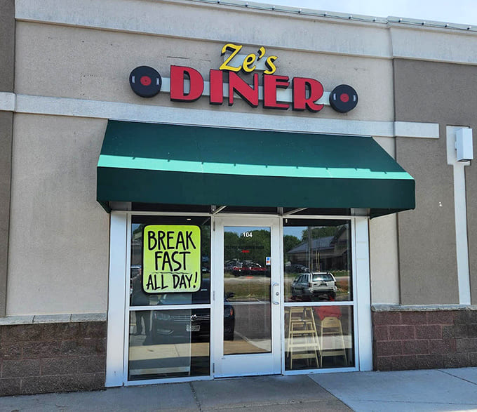 Ze's Diner exterior beckons with its bold red lettering and cheerful green awning &ndash; a time portal disguised as a restaurant entrance.