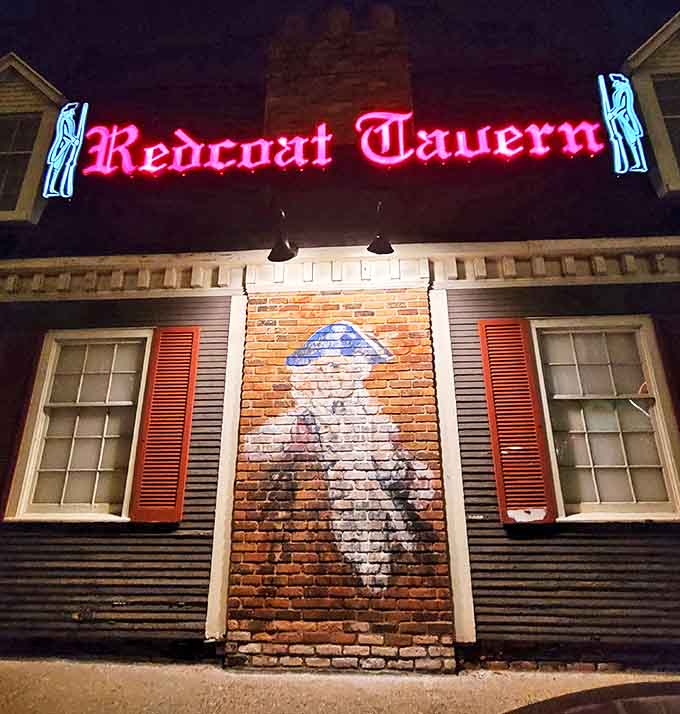 The iconic red neon sign of Redcoat Tavern glows like a beacon for comfort food seekers, promising British-inspired delights within.