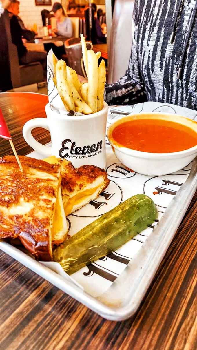Comfort food perfection: grilled cheese with edges crisped to golden glory, tomato bisque for dipping, and that pickle for good measure.
