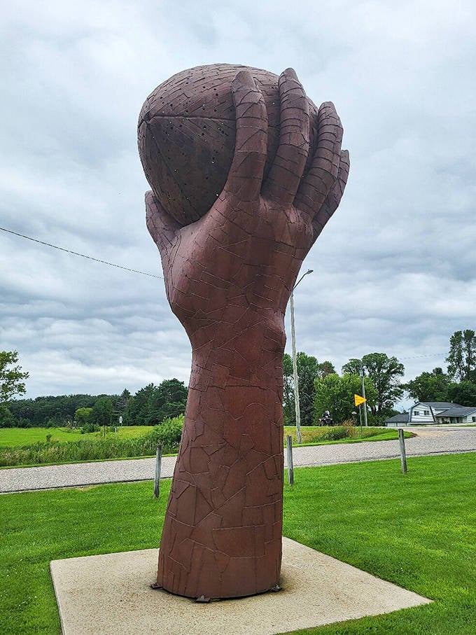 A giant hand cradles a sphere with surprising tenderness. When metal becomes gentle, you know you're witnessing true artistic magic.