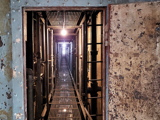 Steel and shadows define this corridor, where the reformatory's industrial design created an atmosphere of constant surveillance and control.