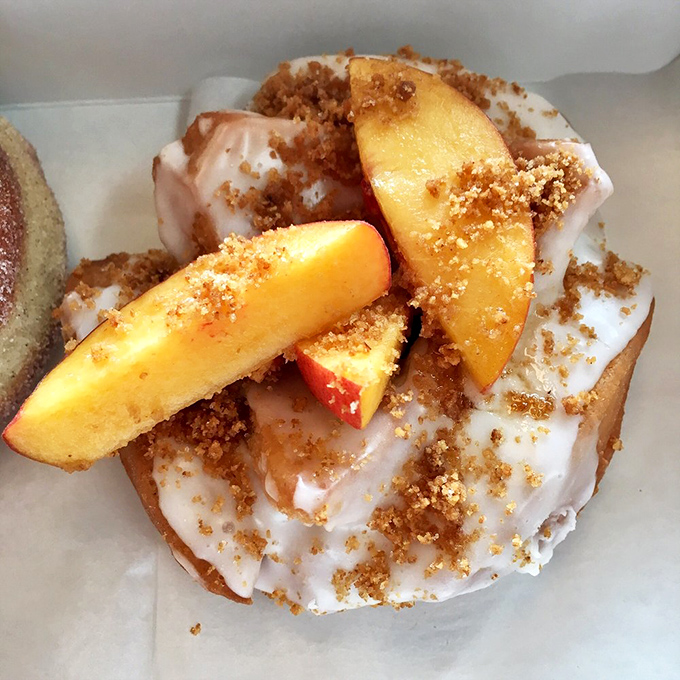 Summer on a donut &ndash; fresh peach slices and buttery streusel crumbles create a seasonal masterpiece that captures Florida's fruit bounty.