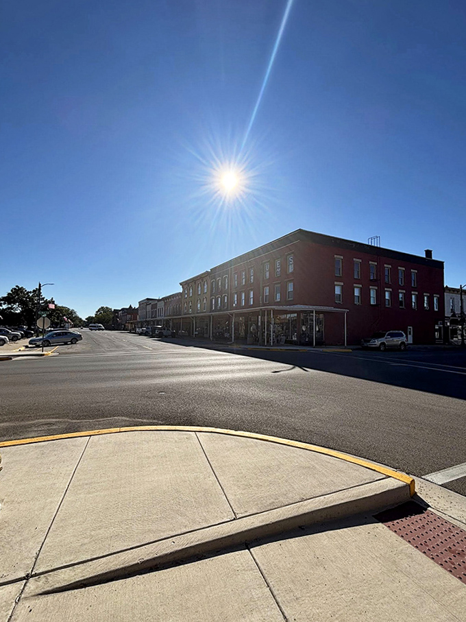 Sunlight bathes the historic corner buildings in golden warmth, highlighting architectural details from an era when craftsmanship mattered.