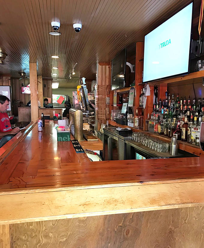 The magnificent wooden bar looks salvaged from an ancient English pub, with bottles gleaming like jewels against the backlit shelving.
