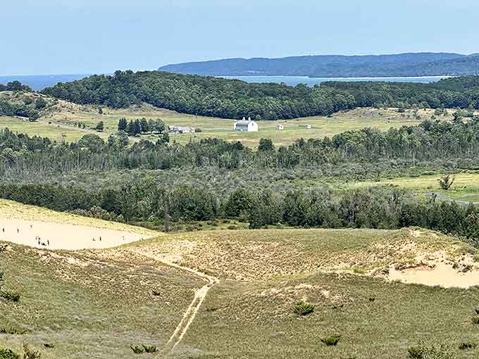 Sand dunes rolling like frozen ocean waves toward the horizon, with farmland nestled below in nature's perfect example of landscape layering.