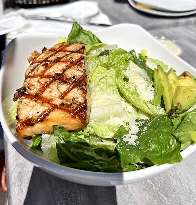 A perfectly grilled salmon fillet atop fresh greens &ndash; the kind of salad that makes you feel virtuous and indulged simultaneously.