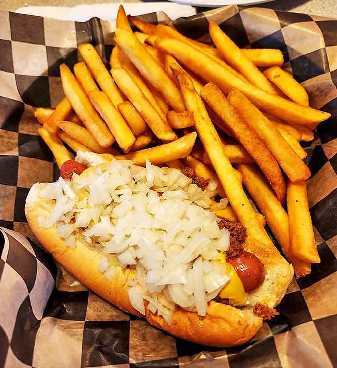 Michigan's beloved Coney dog tradition lives on &ndash; a snappy frank topped with savory meat sauce, diced onions, and mustard alongside golden fries.