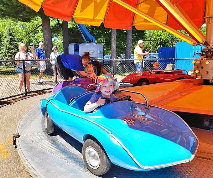Colorful mini-cars circle the track, each young driver wearing that unmistakable expression of concentration mixed with unbridled joy.