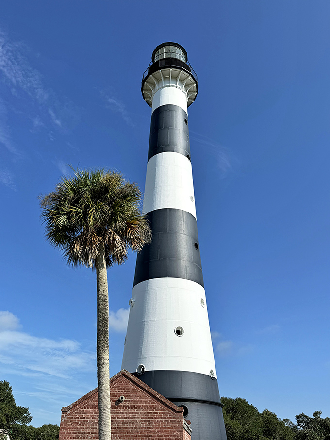 The lighthouse stands majestically against clear skies, its perfect stripes creating a striking silhouette that's become a Space Coast icon.