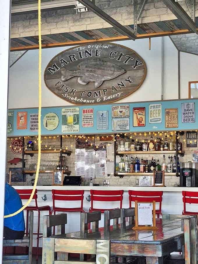 The bar area balances nautical nostalgia with modern flair &ndash; red chairs pop against whitewashed brick while vintage beer signs promise good times ahead.