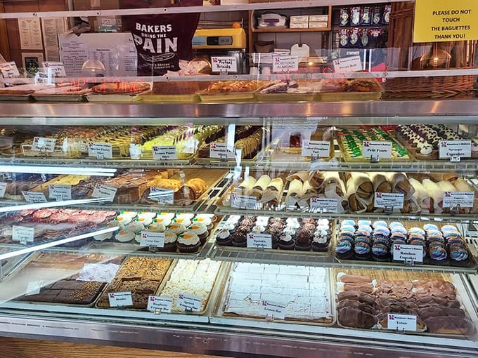 The display case offers a museum-worthy collection of pastries, each shelf a different exhibit in the gallery of deliciousness.