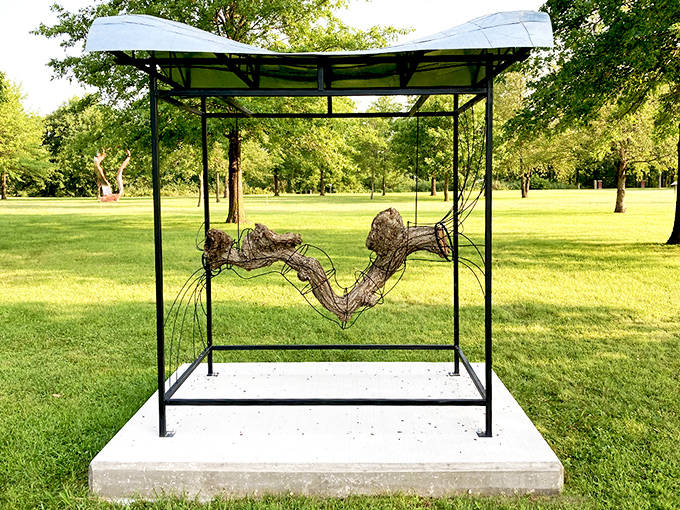 A suspended wire creation catches light and shadow, appearing to float within its protective frame like a three-dimensional sketch in space.