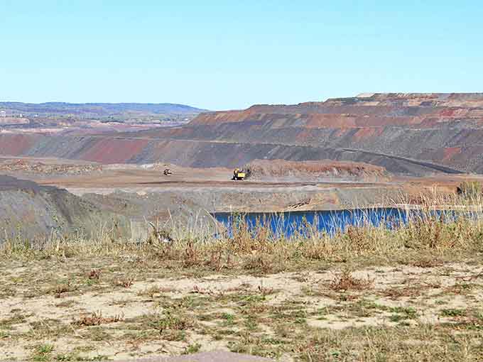 Industrial ballet in progress – massive machines reshape the earth while creating an otherworldly landscape of terraced red walls.