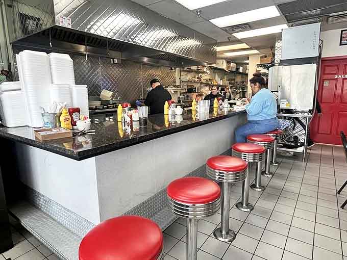 The counter offers front-row seats to short-order magic, where coffee cups never empty and conversation flows as freely as the refills.