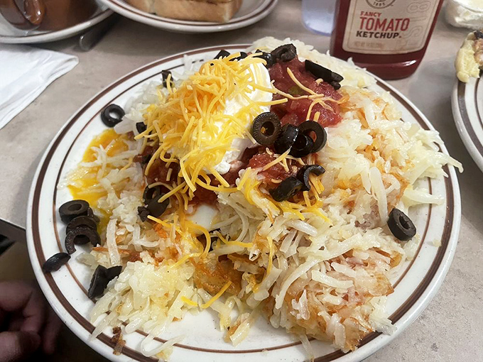 Hash browns loaded with cheese, bacon, and olives &ndash; a savory mountain that proves potatoes are the ultimate breakfast canvas.