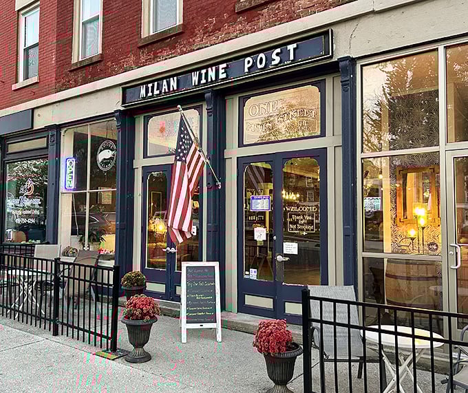 Milan Wine Post invites passersby with warm lighting and American flags, promising sophisticated sips in historic surroundings.