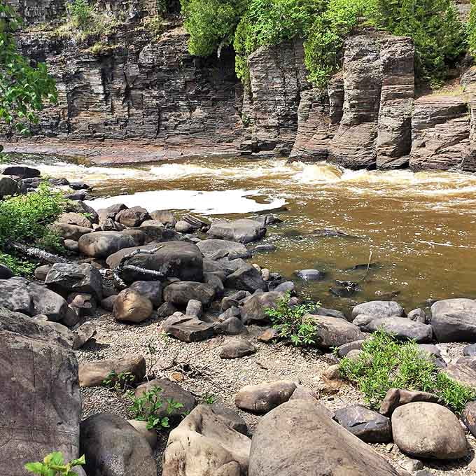 Nature's patient artwork: Centuries of flowing water have polished these riverside rocks into smooth sentinels guarding the Pigeon River's journey.