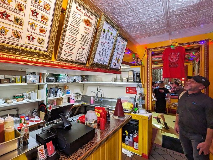 Behind this counter, hot dog dreams come true. The framed menus and colorful workspace look like the command center for delicious decisions.