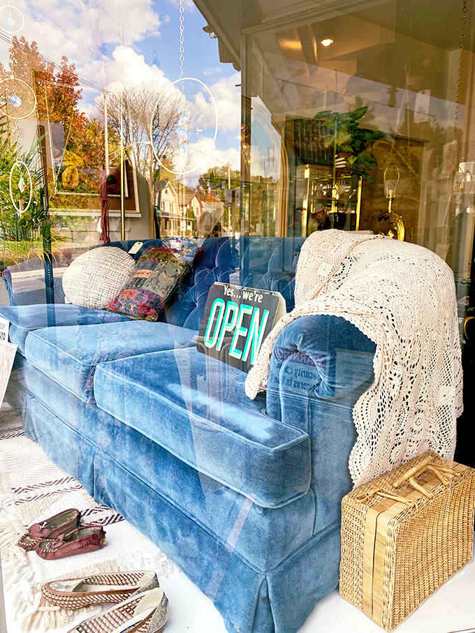 A blue velvet sofa sits outside with an "Open" sign, because when your inventory is this good, you need to advertise with style and comfort.