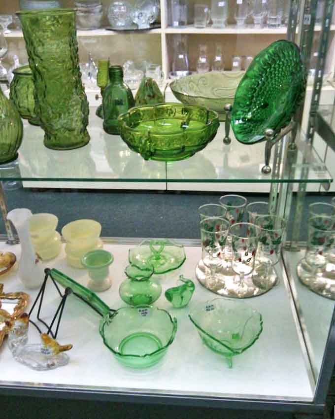 The emerald glow of Depression glass transforms ordinary shelves into a treasure trove of collectibles, each piece holding the distinctive patterns that collectors covet.