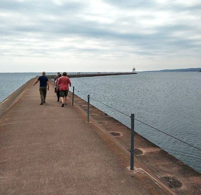 Fellow explorers make the pilgrimage along the breakwater, drawn by the same magnetic pull that's attracted visitors for generations.