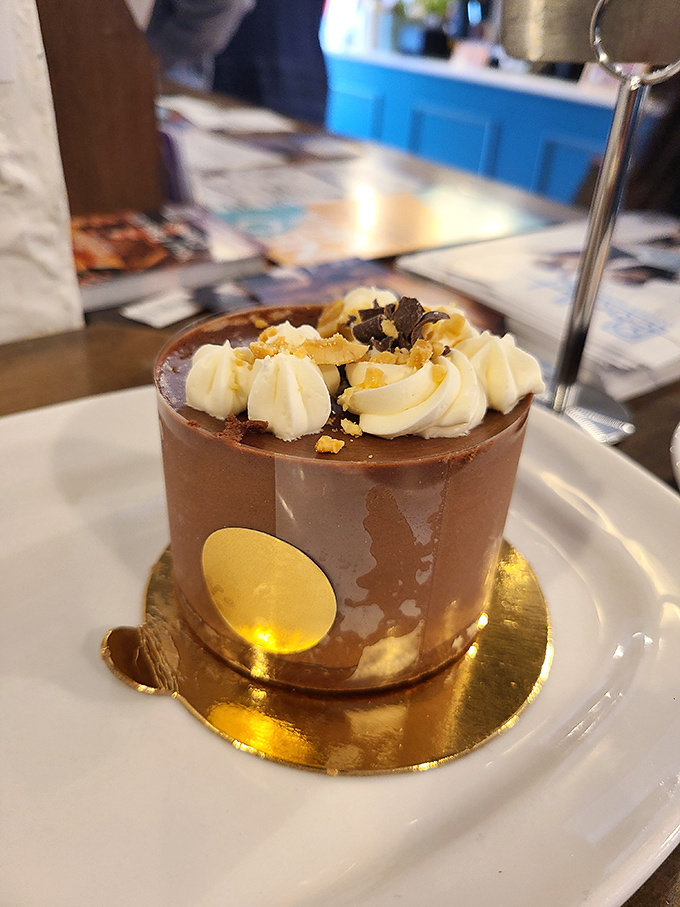 The chocolate mousse cake gleams with ganache perfection, topped with dollops of cream that promise to dissolve on your tongue. 