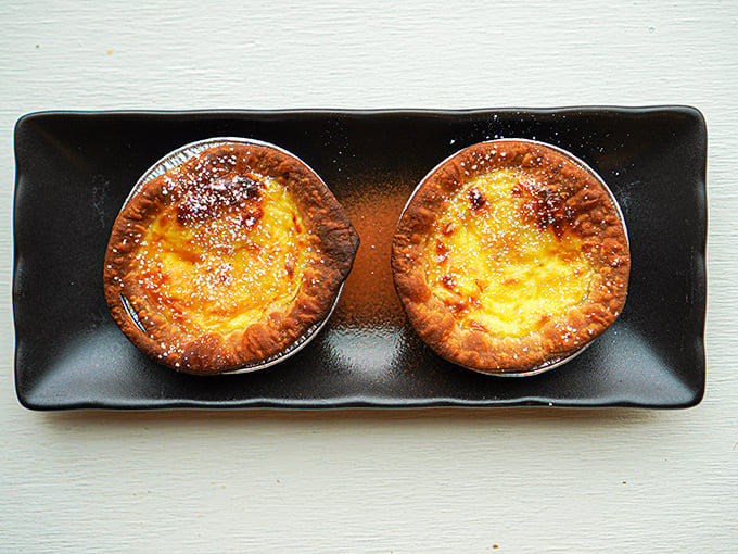 These golden custard tarts offer sweet redemption after a spicy meal &ndash; their delicate, flaky crusts hiding creamy centers that soothe heat-punished taste buds.