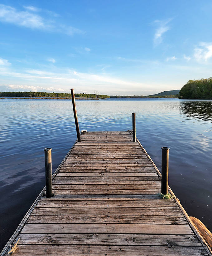 Weathered planks stretch into glassy waters, offering the perfect launch pad for fishing dreams and sunset contemplation.