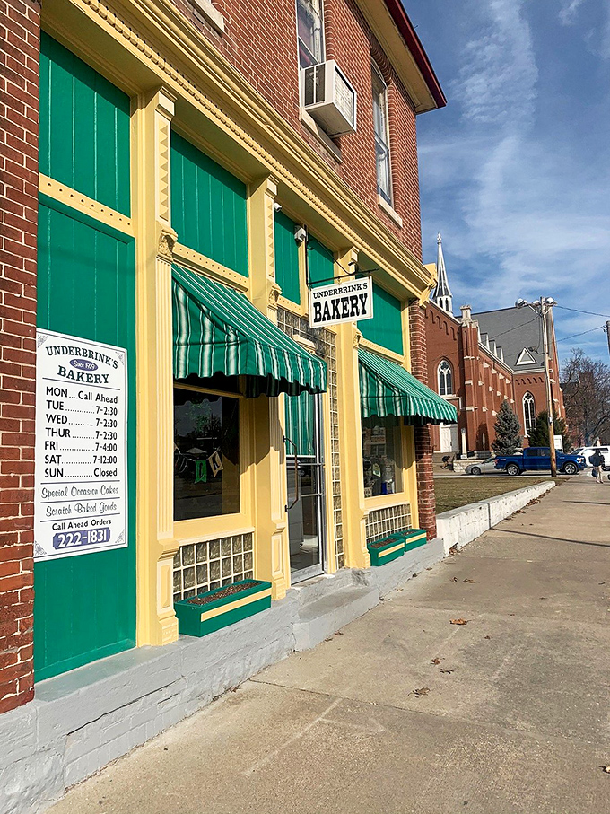 Green awnings and yellow trim create a storybook facade that promises delicious plot twists waiting just inside those doors.