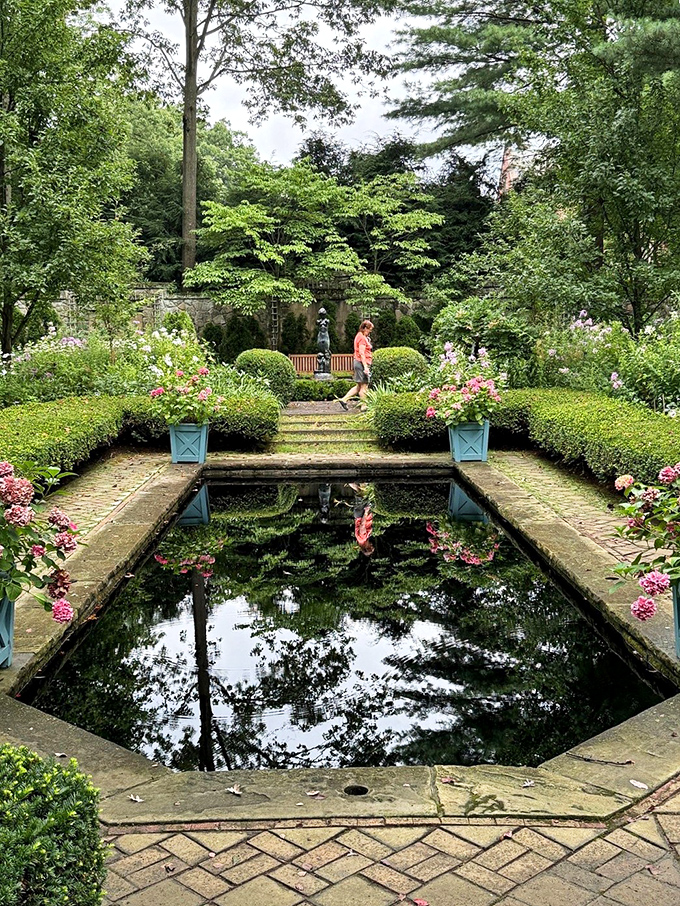 Reflections double the beauty in this formal garden pool, where geometric precision meets the organic charm of blooming perennials.