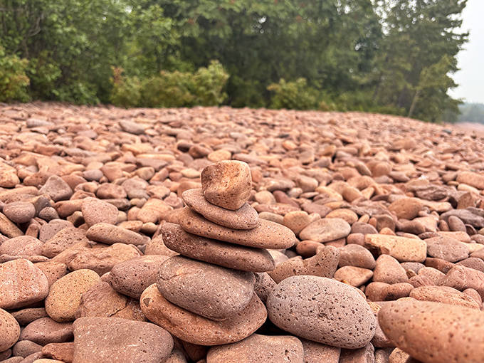 The beach stretches into the distance, its distinctive pink-red hue creating a stunning contrast with the deep blue of Lake Superior.