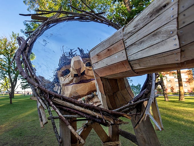 Peek-a-boo with a wooden giant! This troll's face emerges from a handcrafted circular frame, blending artistic vision with natural materials in a playful park installation.