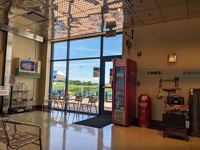 The waiting area blends aviation history with diner charm – vintage Coca-Cola machines stand guard near views of the airfield beyond.