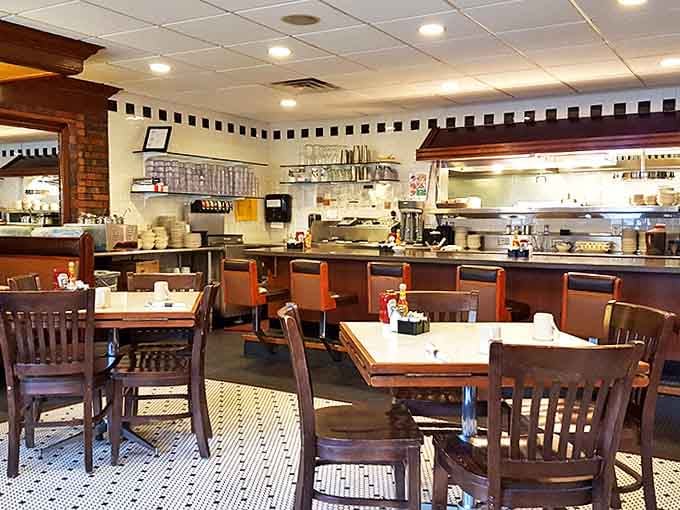 The open kitchen concept lets diners watch the culinary choreography while servers navigate the classic tile floor with practiced precision.