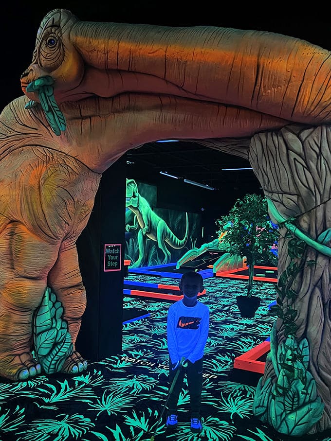 The brachiosaurus entrance creates a Jurassic welcome, its long neck arching over visitors like a glowing gateway to prehistoric putting adventures.