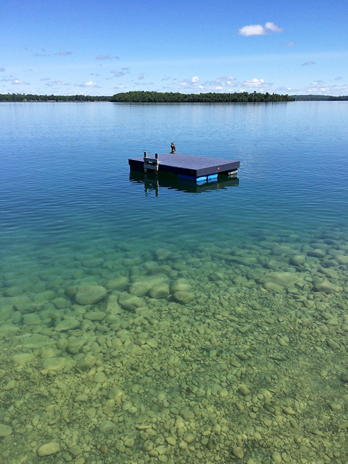 A solitary swimming platform awaits summer visitors, floating above Deer Lake's remarkably clear waters and stone-scattered bottom.
