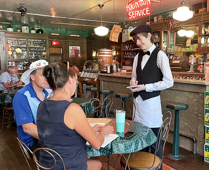 The bow-tied server takes orders with the serious concentration of someone who knows they're delivering happiness, not just dessert.