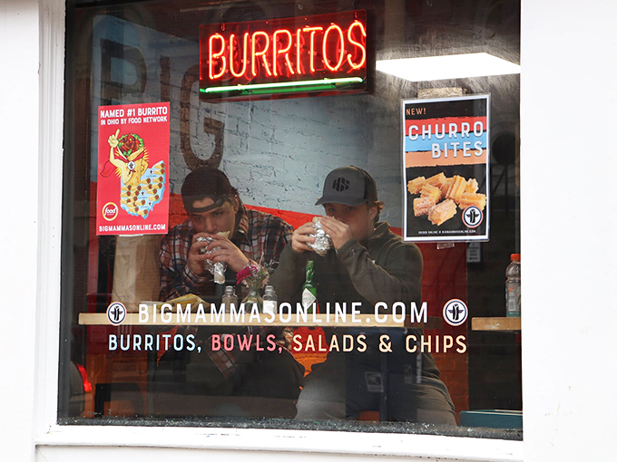 Diner: Through the window, we glimpse the sacred ritual of burrito consumption &ndash; heads bowed not in prayer but in devoted appreciation.