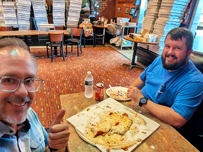 Two happy customers giving the universal sign for "this pizza has changed our lives for the better."