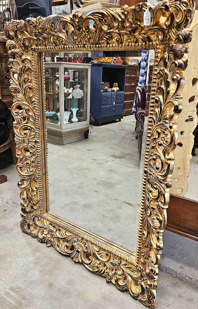 An ornately carved gold mirror that doesn't just reflect your image – it frames you like the protagonist in your own period drama.